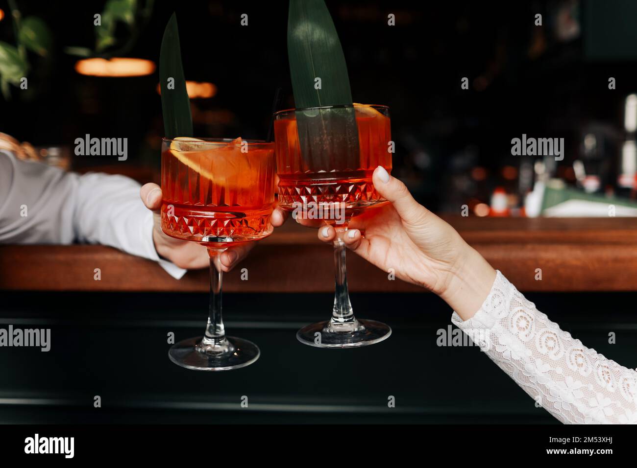hands of woman and man are clinking, cheers with glasses of Spritz ...