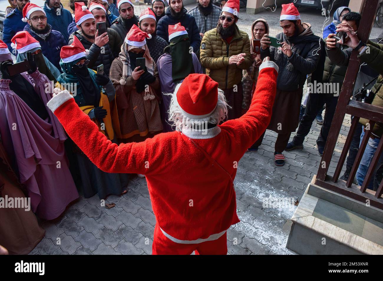 A devotee dressed in Santa Clause costume performs in front of the ...
