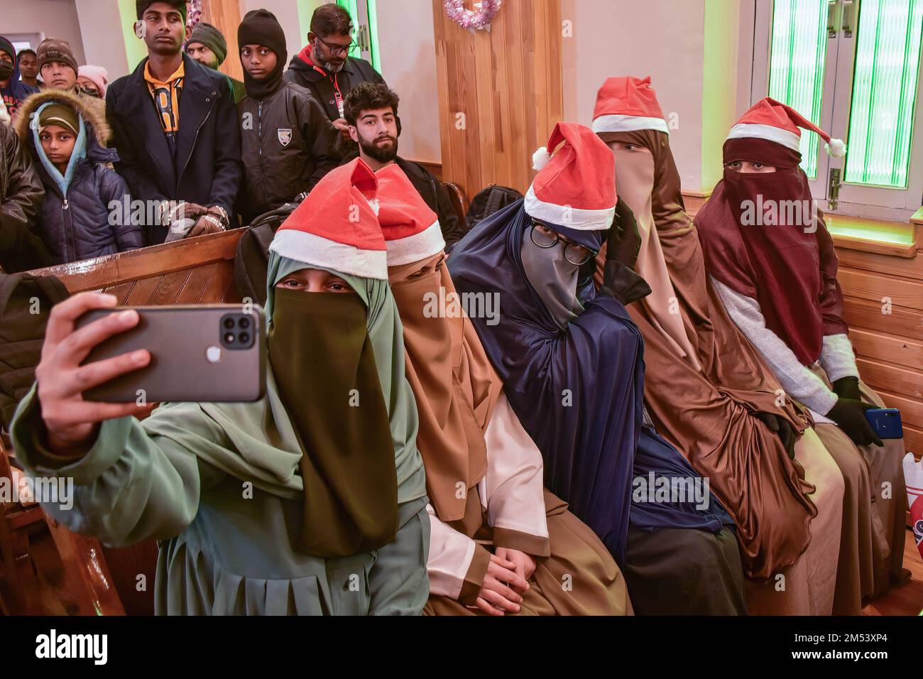 Kashmiri Muslim veiled women wearing Santa Clause caps take a selfie as ...