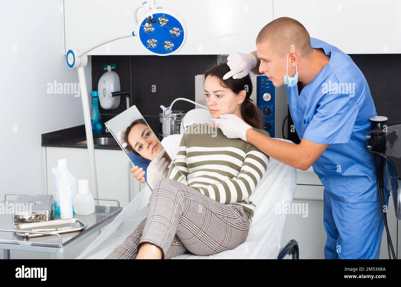 Beautician examining female face skin after procedure Stock Photo - Alamy