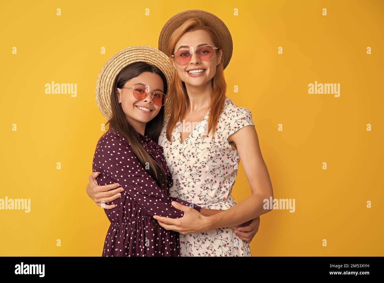 positive mother and daughter in straw hat on yellow background Stock ...