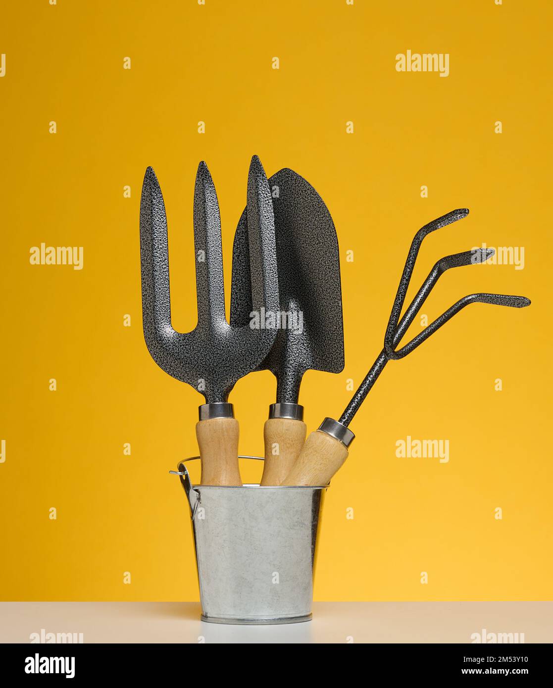 Miniature garden tools in a metal bucket on a yellow background Stock ...