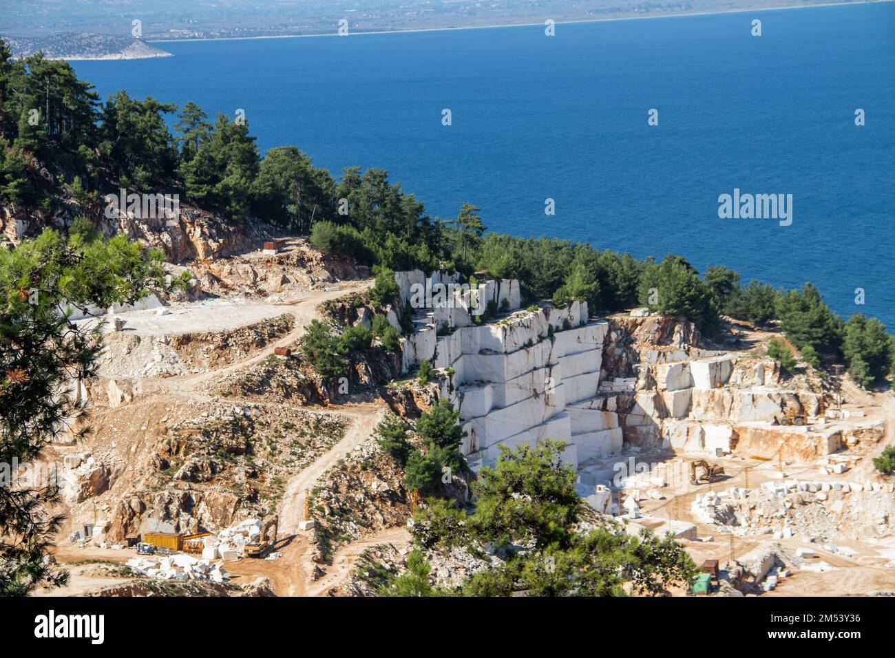 An open-pit mine of white marble stone with heavy machinery used to ...