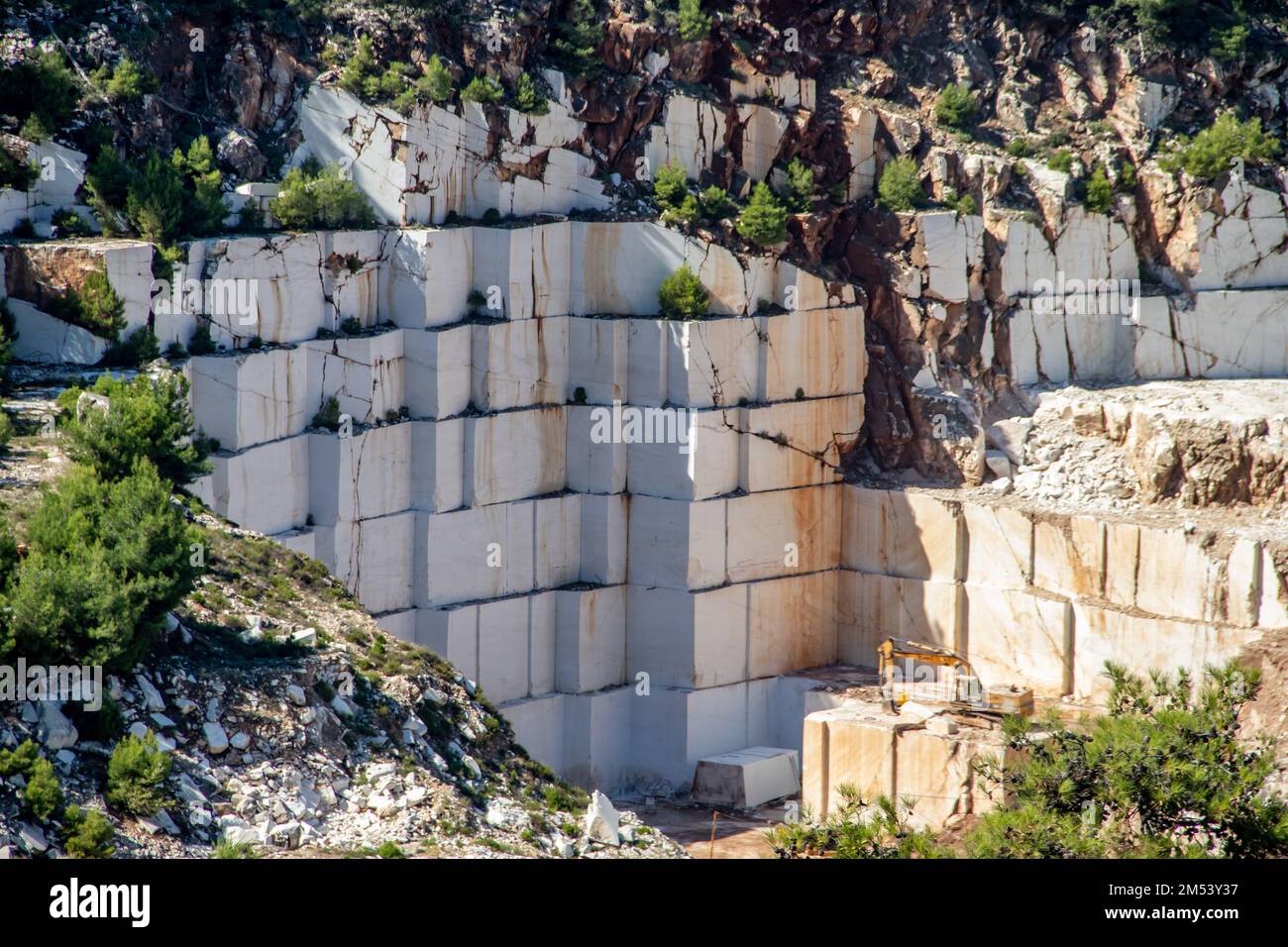 An open-pit mine of white marble stone with heavy machinery used to ...