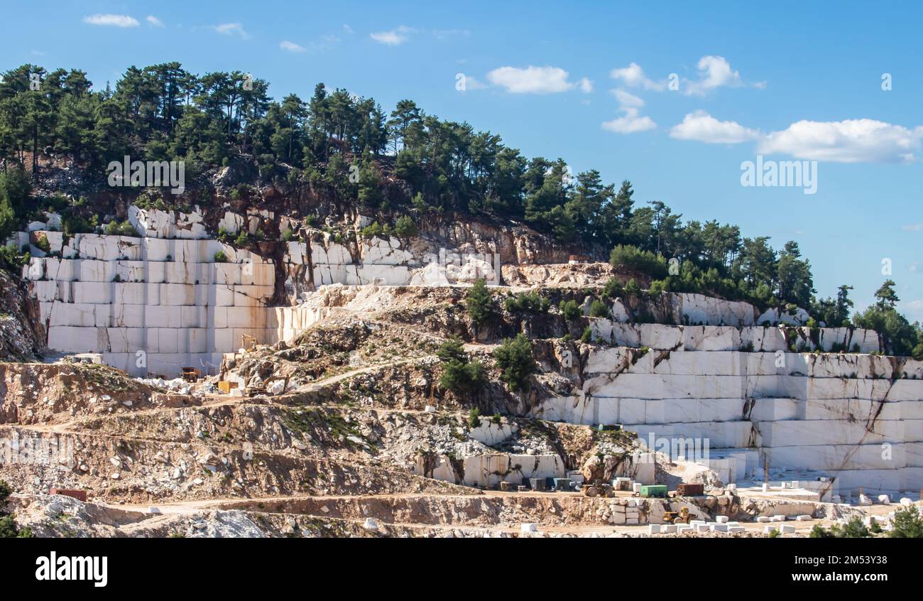 An open-pit mine of white marble stone with heavy machinery used to ...