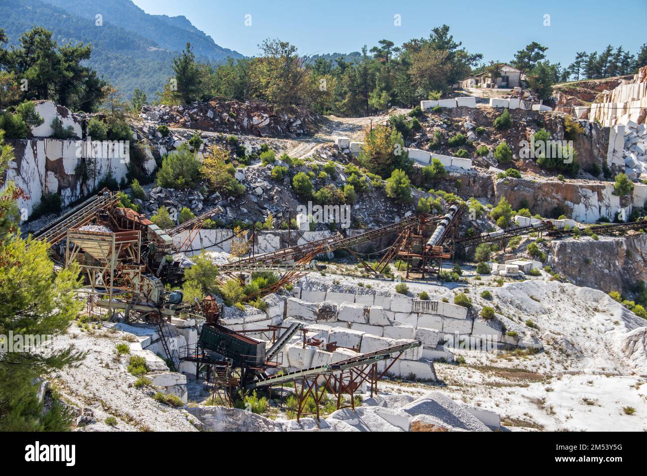 An open-pit mine of white marble stone with heavy machinery used to ...