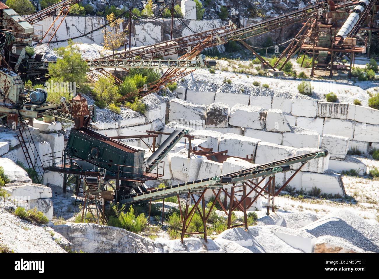 An open-pit mine of white marble stone with heavy machinery used to ...