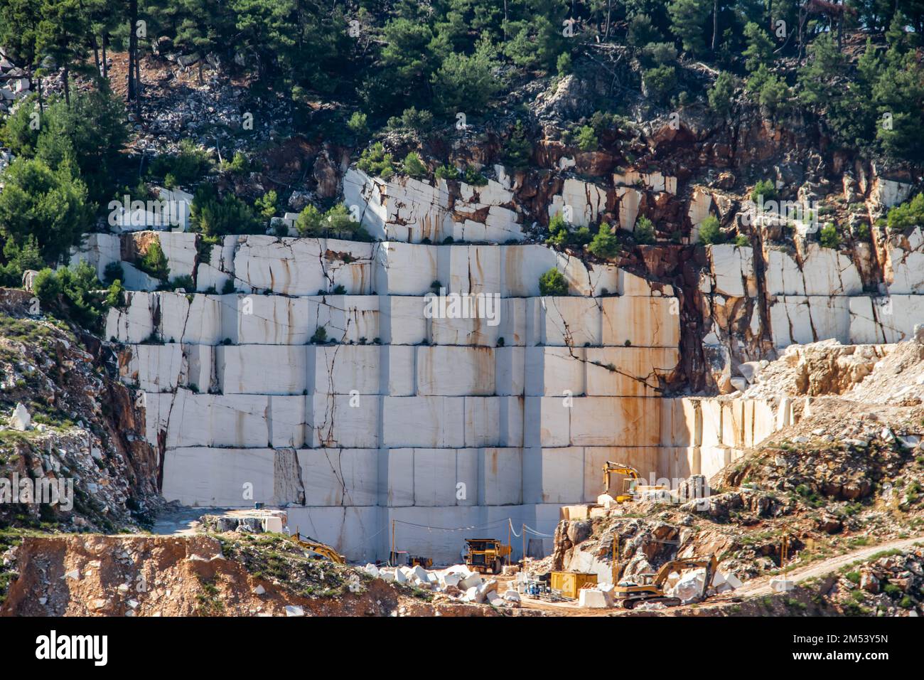 An open-pit mine of white marble stone with heavy machinery used to ...