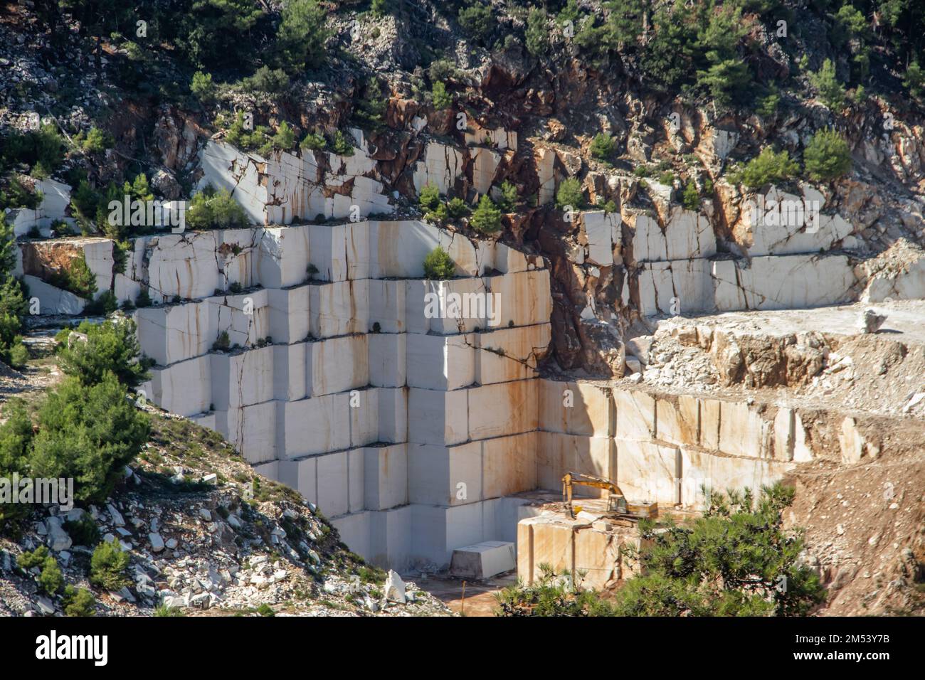 An open-pit mine of white marble stone with heavy machinery used to ...