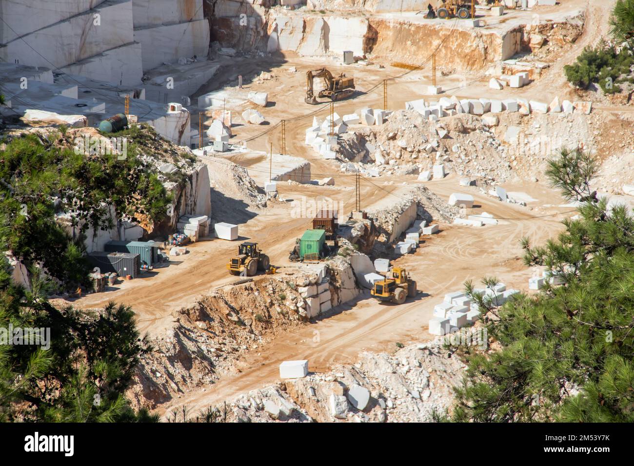 An open-pit mine of white marble stone with heavy machinery used to ...