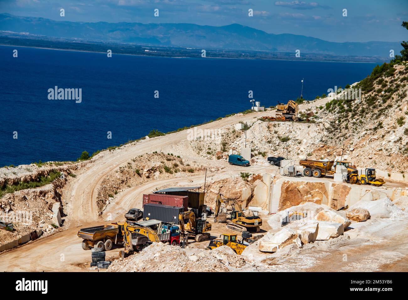 An open-pit mine of white marble stone with heavy machinery used to ...