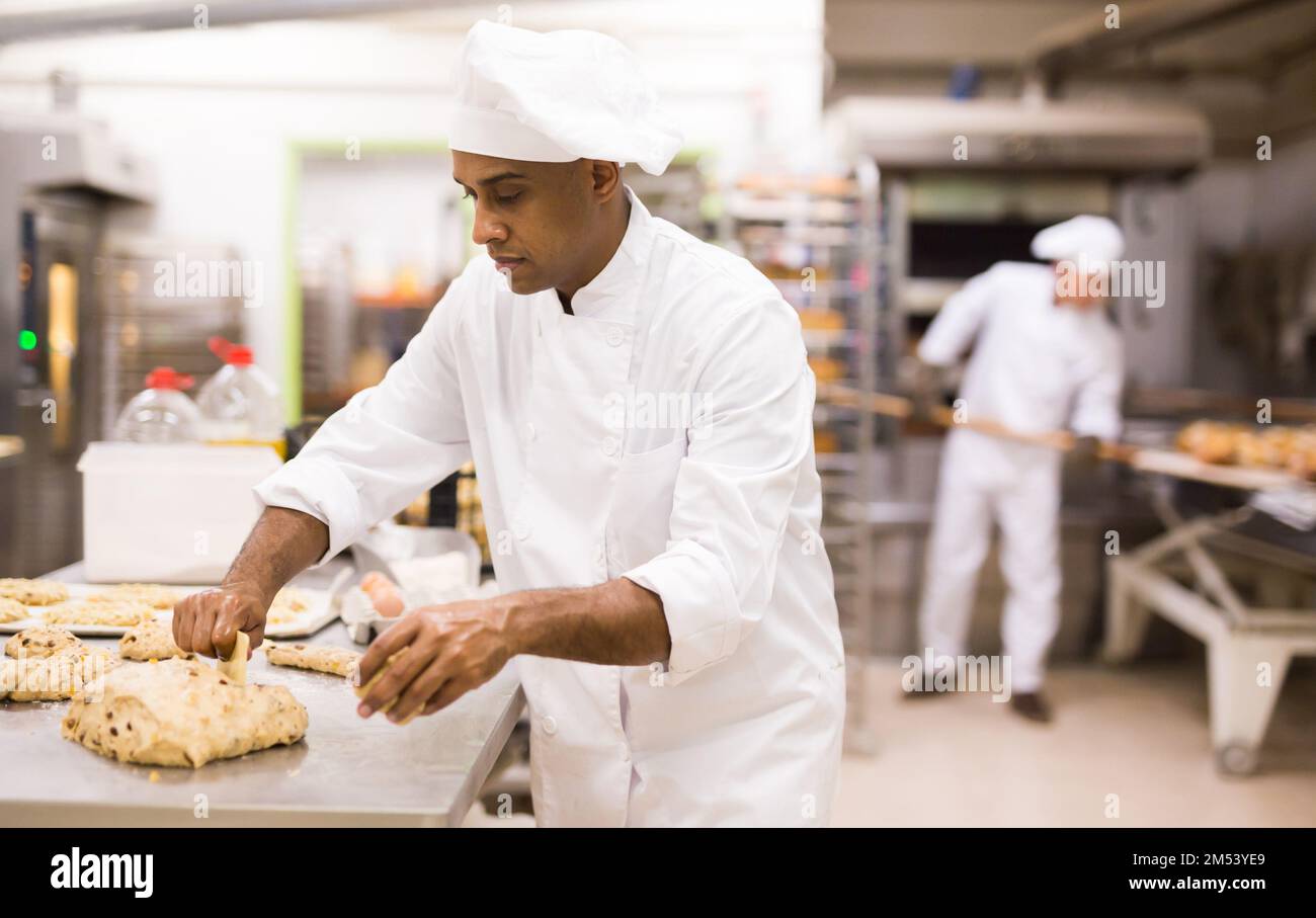 portrait of latino male baker making cookies in bakehouse Stock Photo ...
