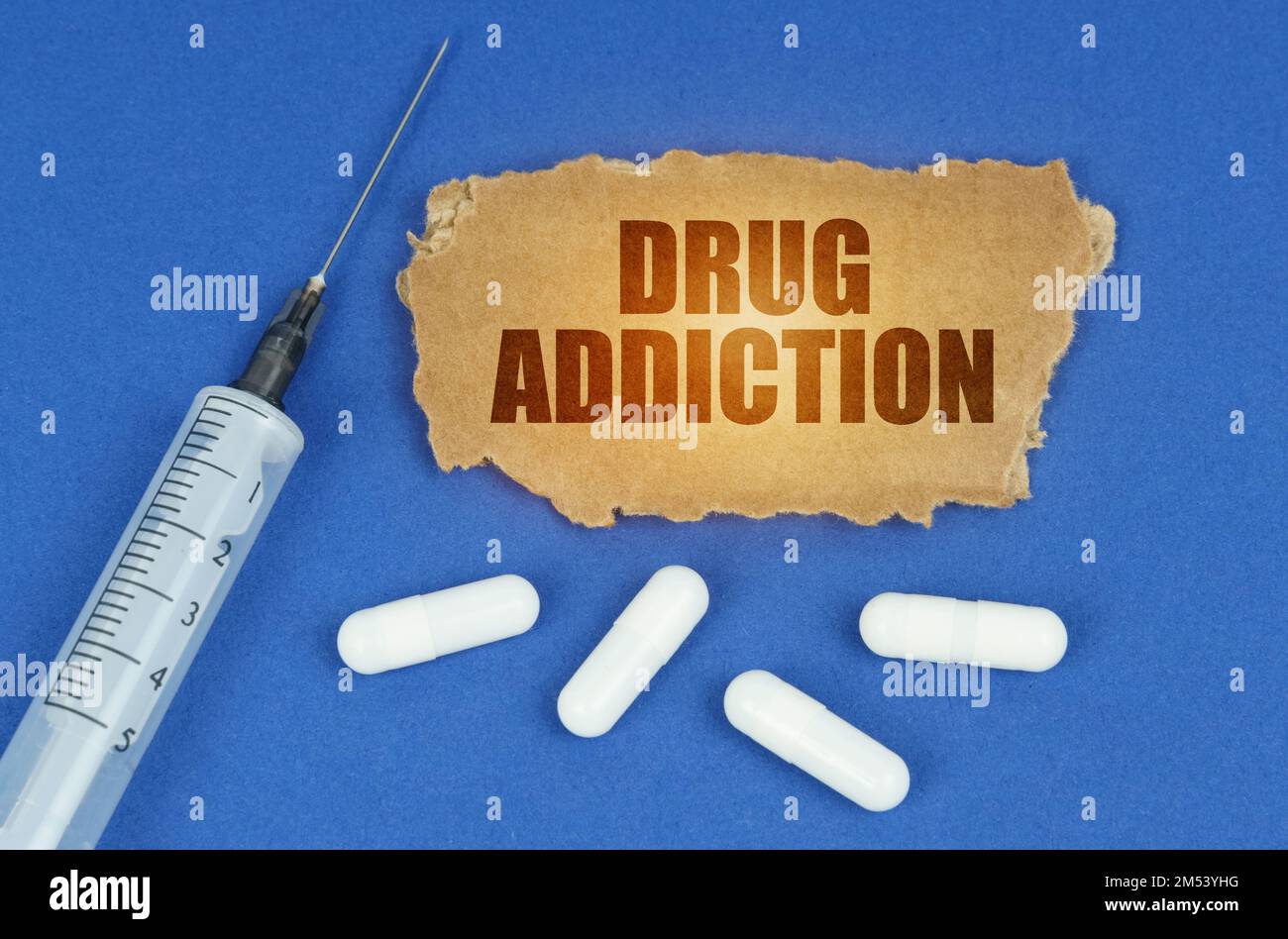 Medical concept. On a blue surface lie a syringe, pills and a cardboard ...