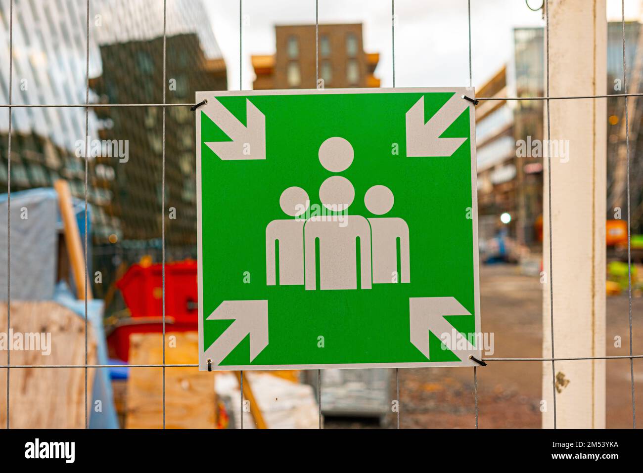 A closeup of Assembly point sign on a fence by a construction site ...