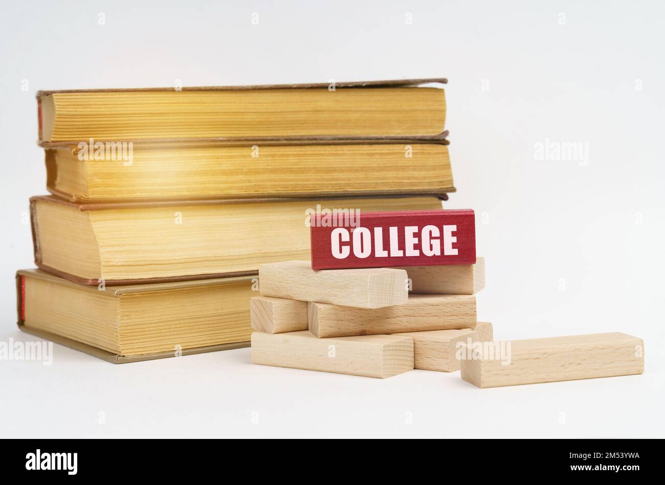 Education concept. On a white surface, a stack of books and wooden ...