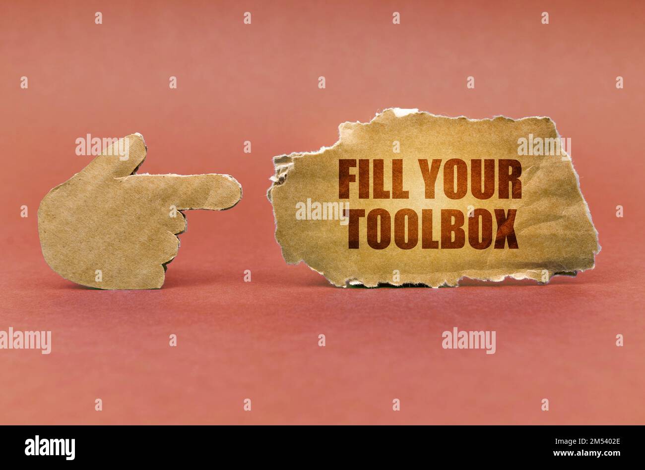 Industrial concept. On a brown surface, a cardboard hand points to a sign that says - Fill Your ...
