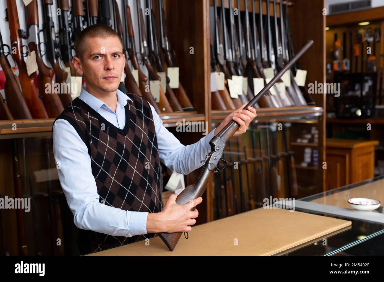 Male owner of armory shop offering vintage hunting rifle Stock Photo ...