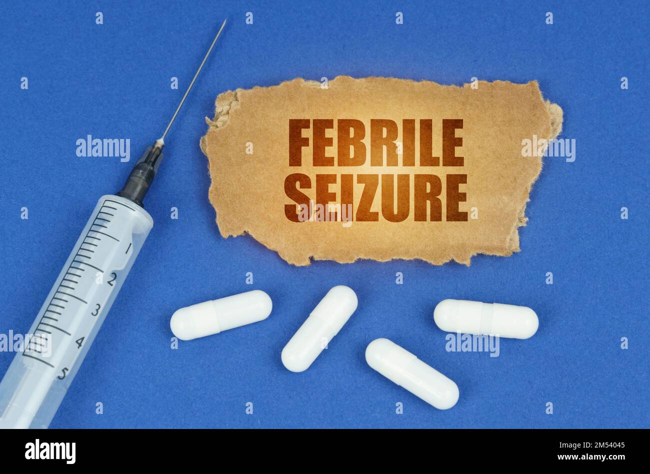 Medical concept. On a blue surface lie a syringe, pills and a cardboard ...