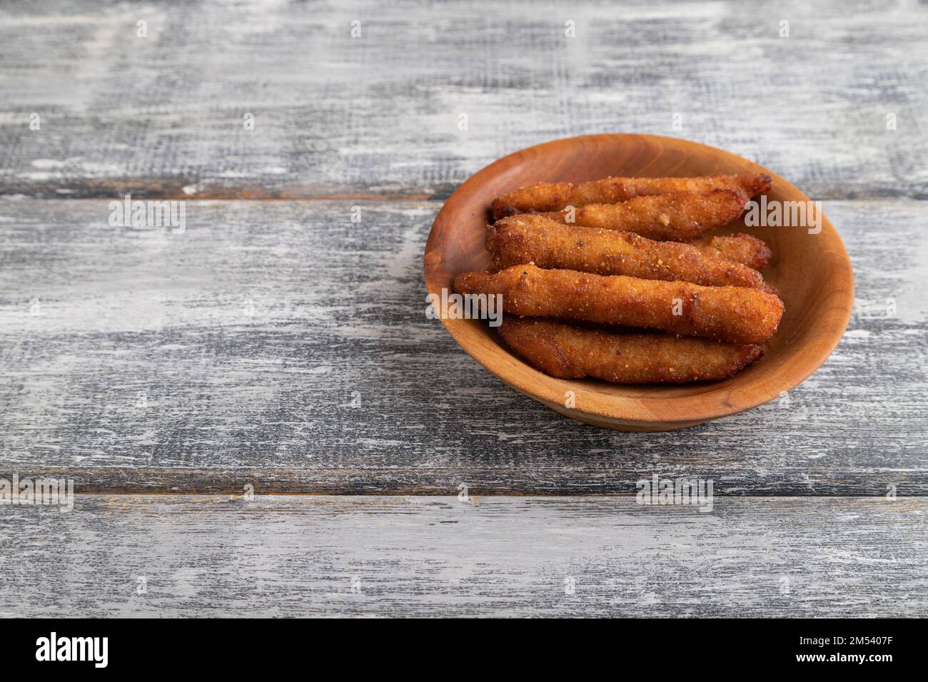 Chicken nuggets on a wooden plate on a gray wooden background. Side ...