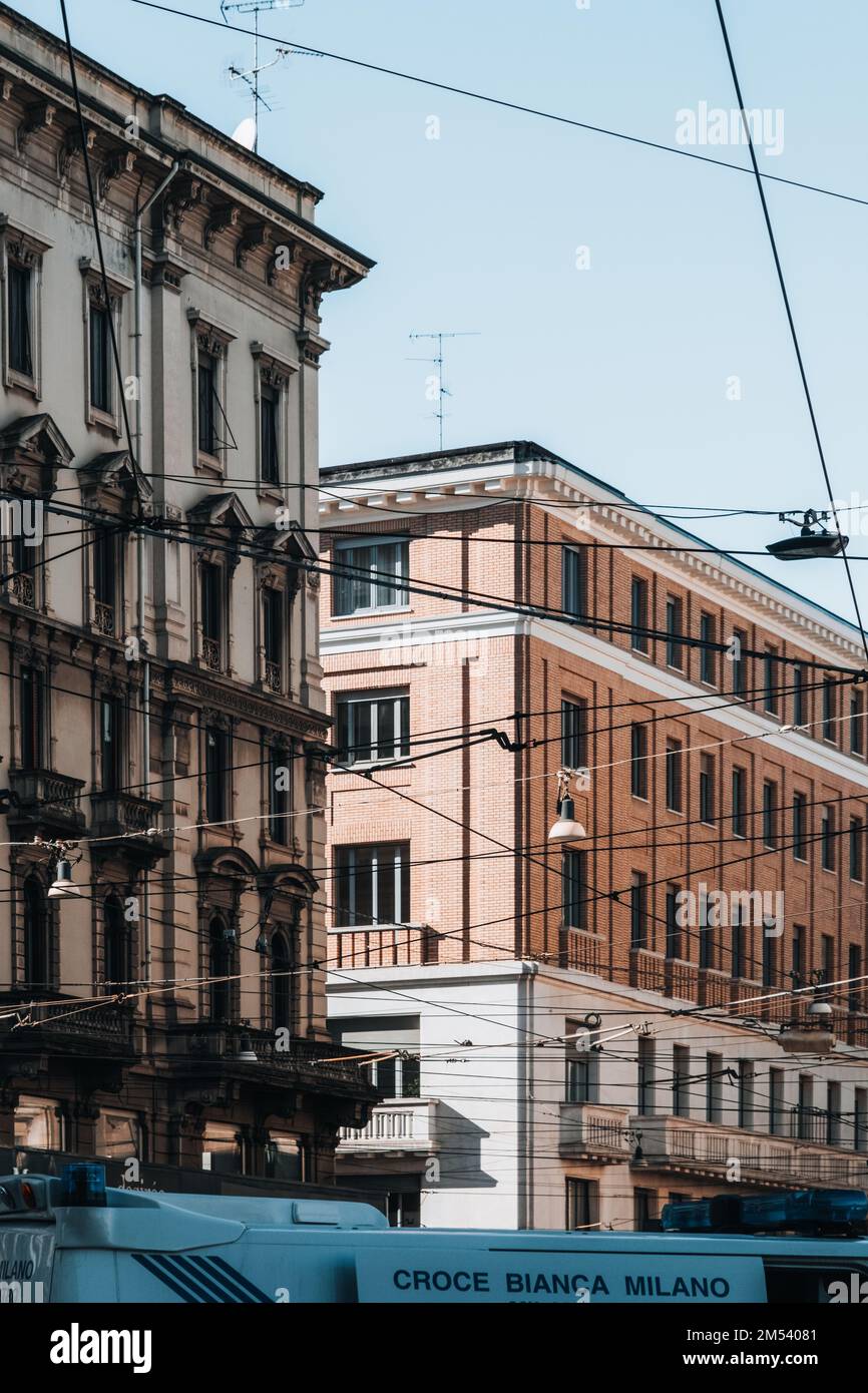 A vertical shot of stylish beige buildings and a top of a white tram in ...