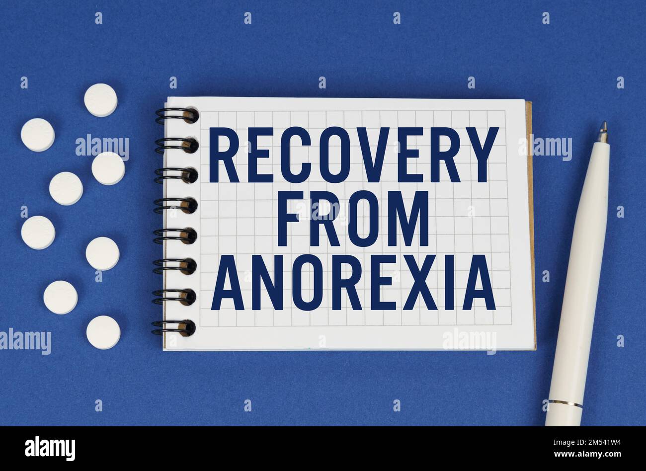 Medical concept. On a blue background, a pen, tablets and a notepad ...