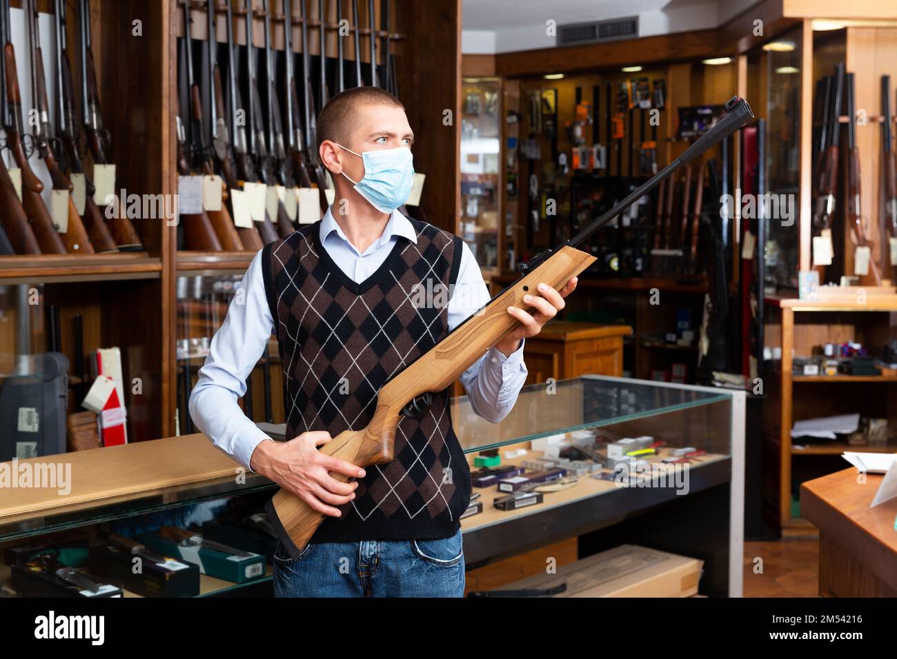 Gun store owner in medical mask offering break-barrel air rifle Stock ...