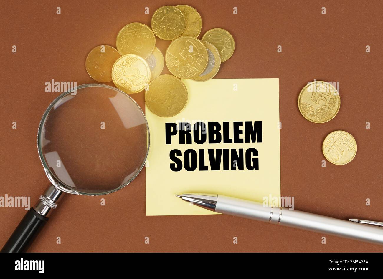 Business concept. On a brown surface are coins, a pen, a magnifying ...