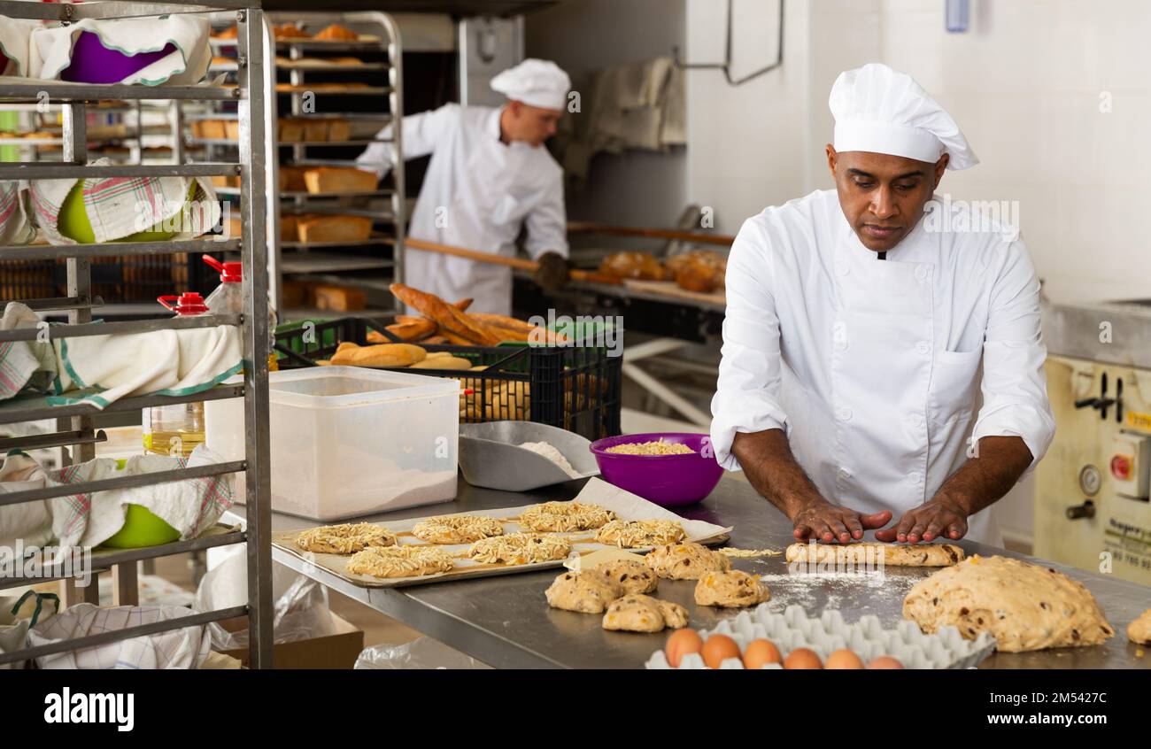 Male baker working with dough forming baguettes Stock Photo - Alamy