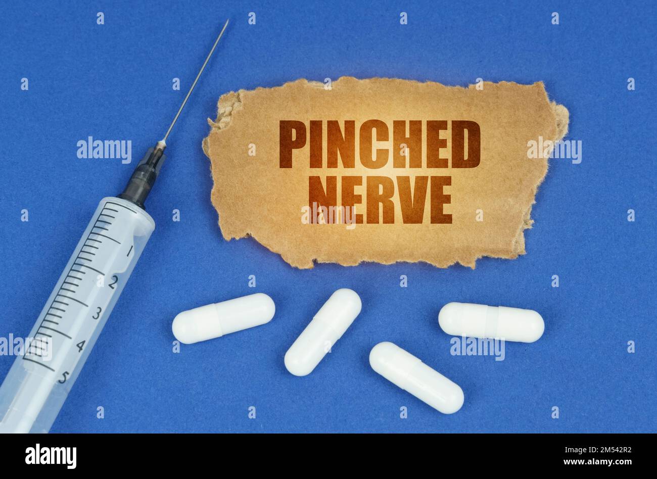 Medical concept. On a blue surface lie a syringe, pills and a cardboard ...