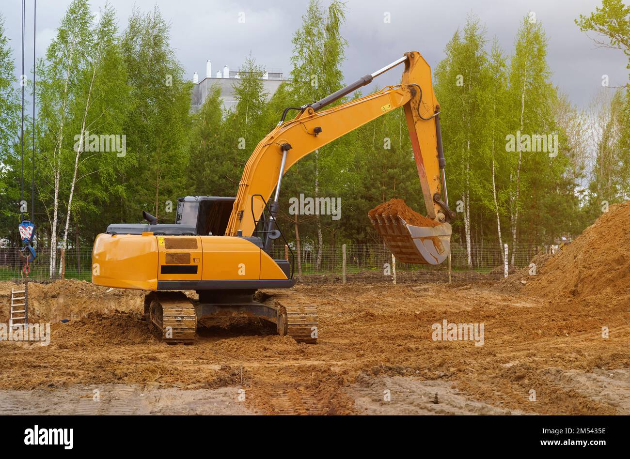 Building concept. An excavator is digging a pit for a house Stock Photo ...