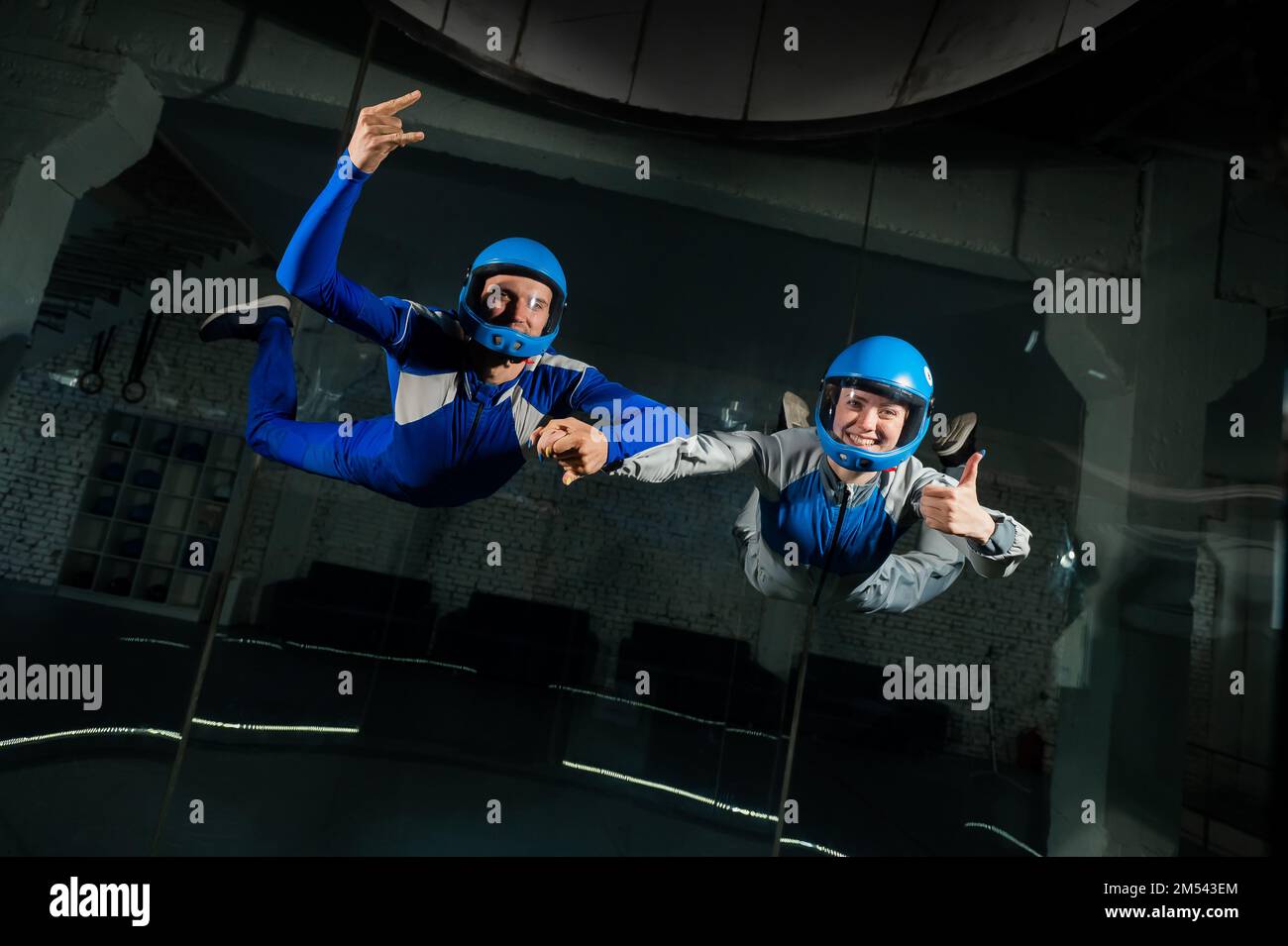 A man teaches a woman how to fly in a wind tunnel. Free fall simulator ...