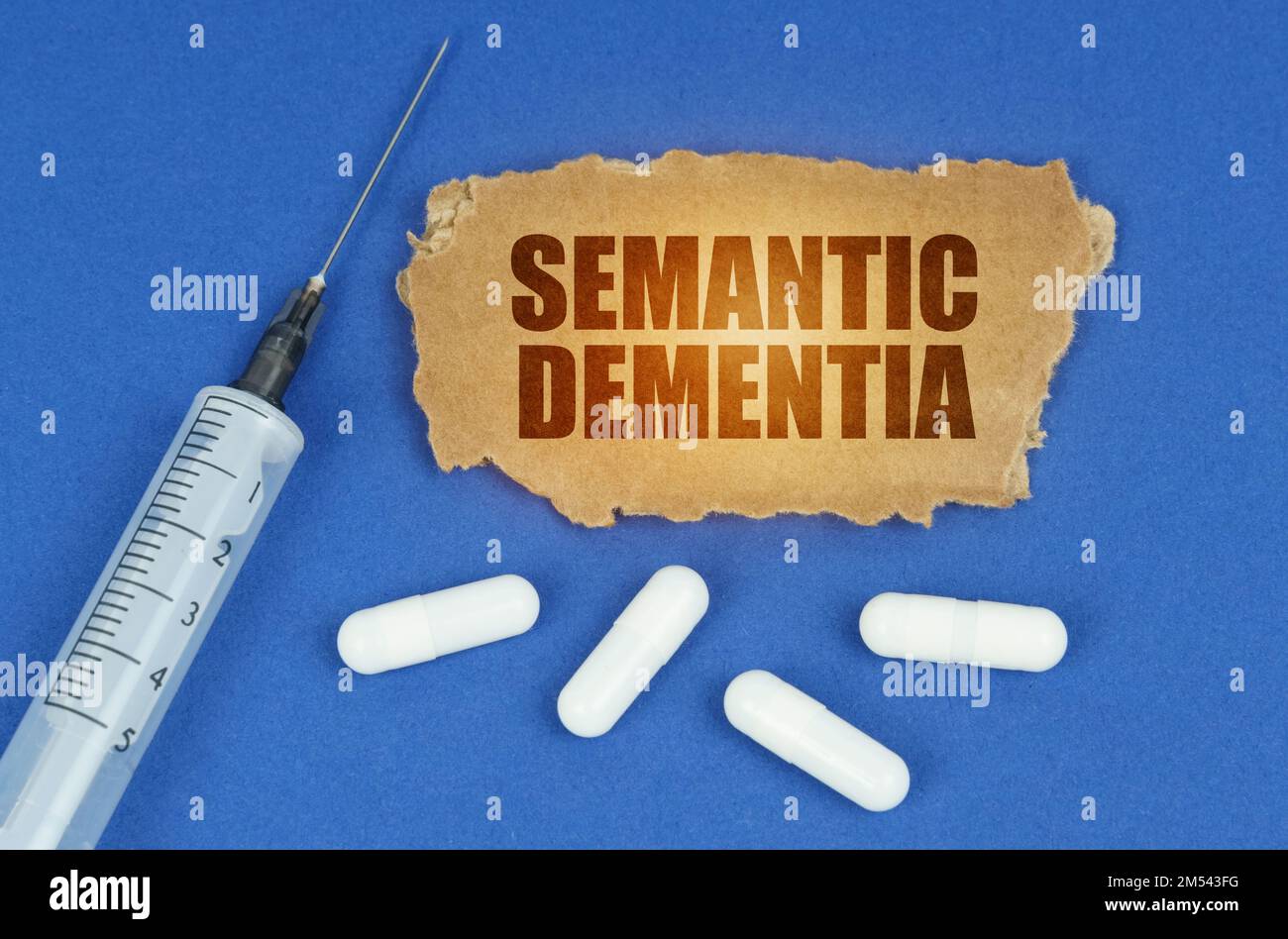 Medical concept. On a blue surface lie a syringe, pills and a cardboard ...