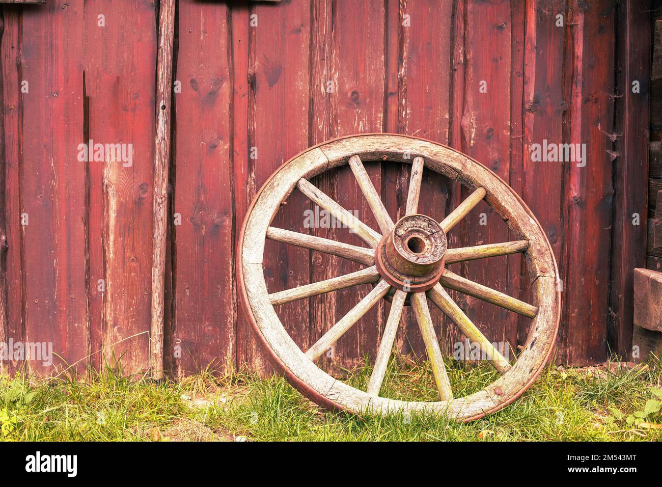 Old rusty wagon wheel leans against barn.Peasant tool Stock Photo - Alamy