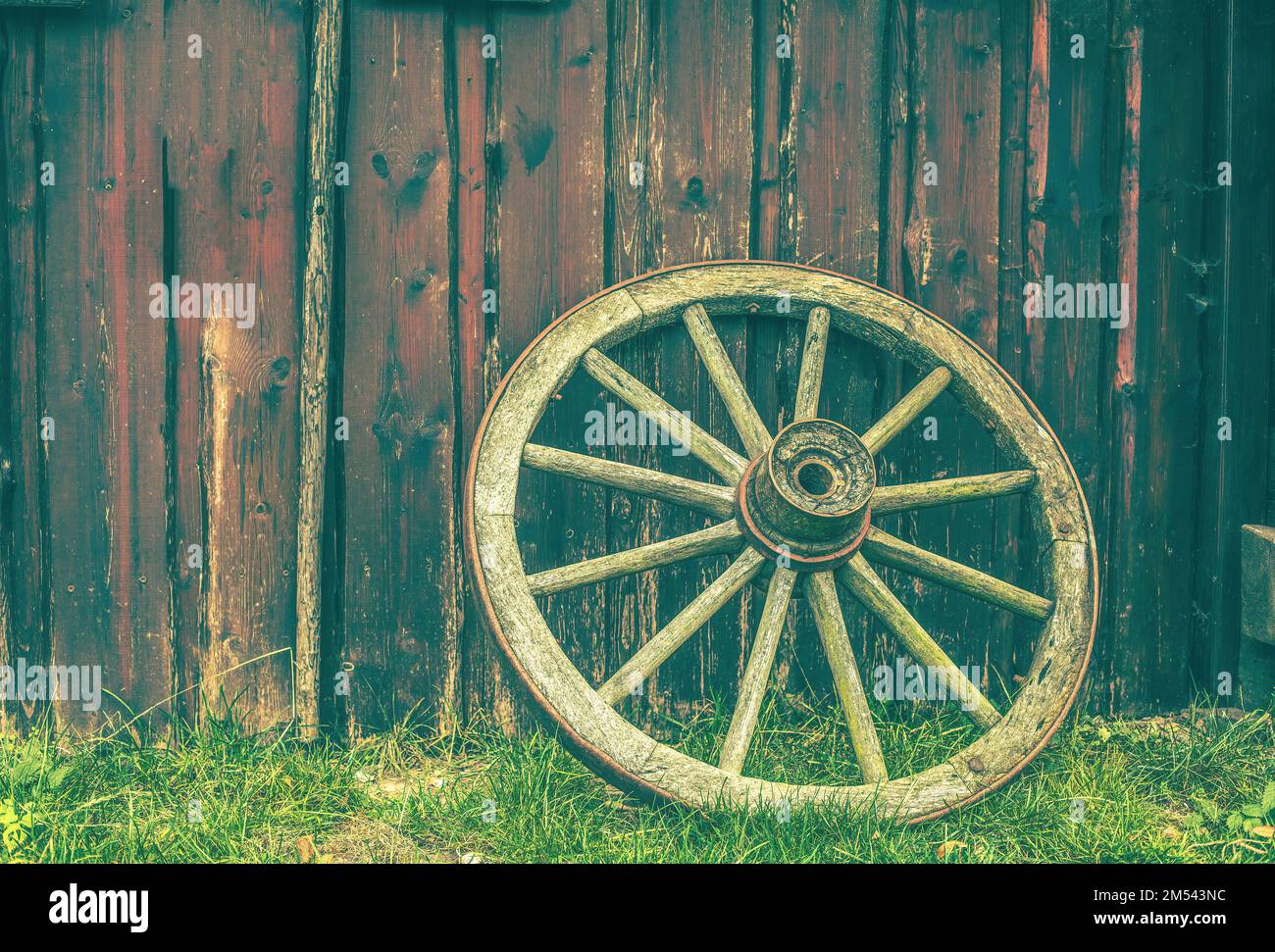 Old rusty wagon wheel leans against barn.Peasant tool Stock Photo - Alamy