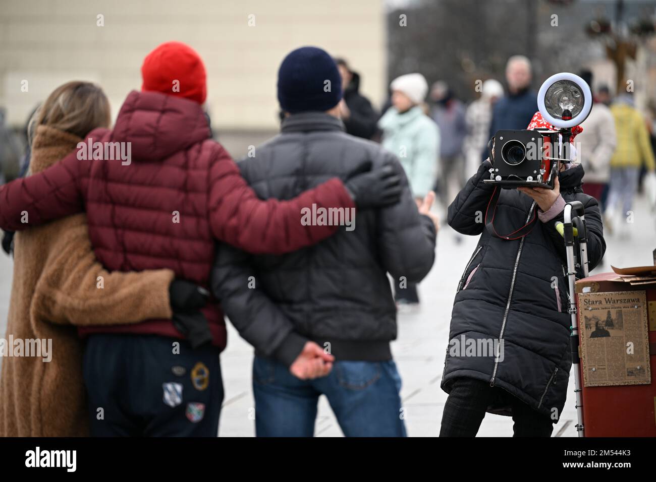 A photographer takes photos of tourists with a mock large format camera ...