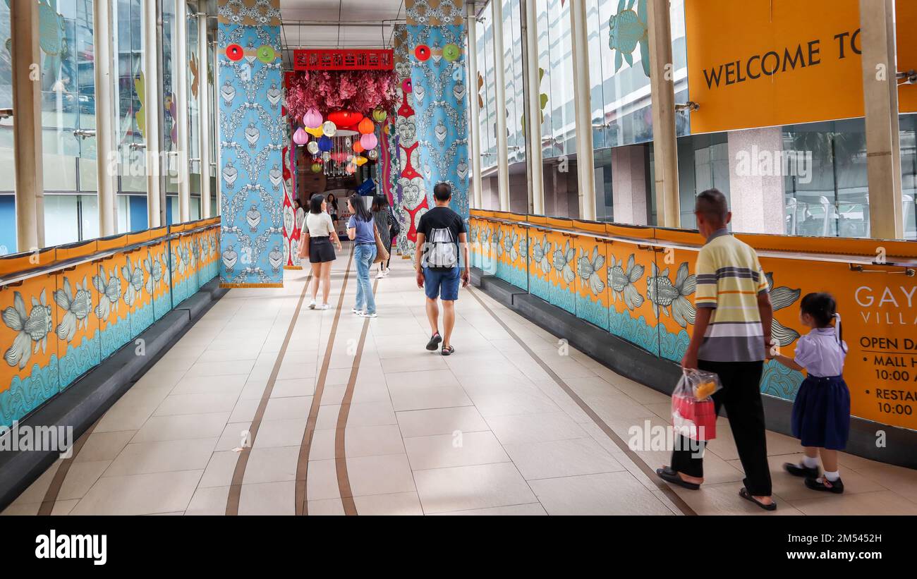 A colorful tunnel of a shopping mall with people walking through it ...