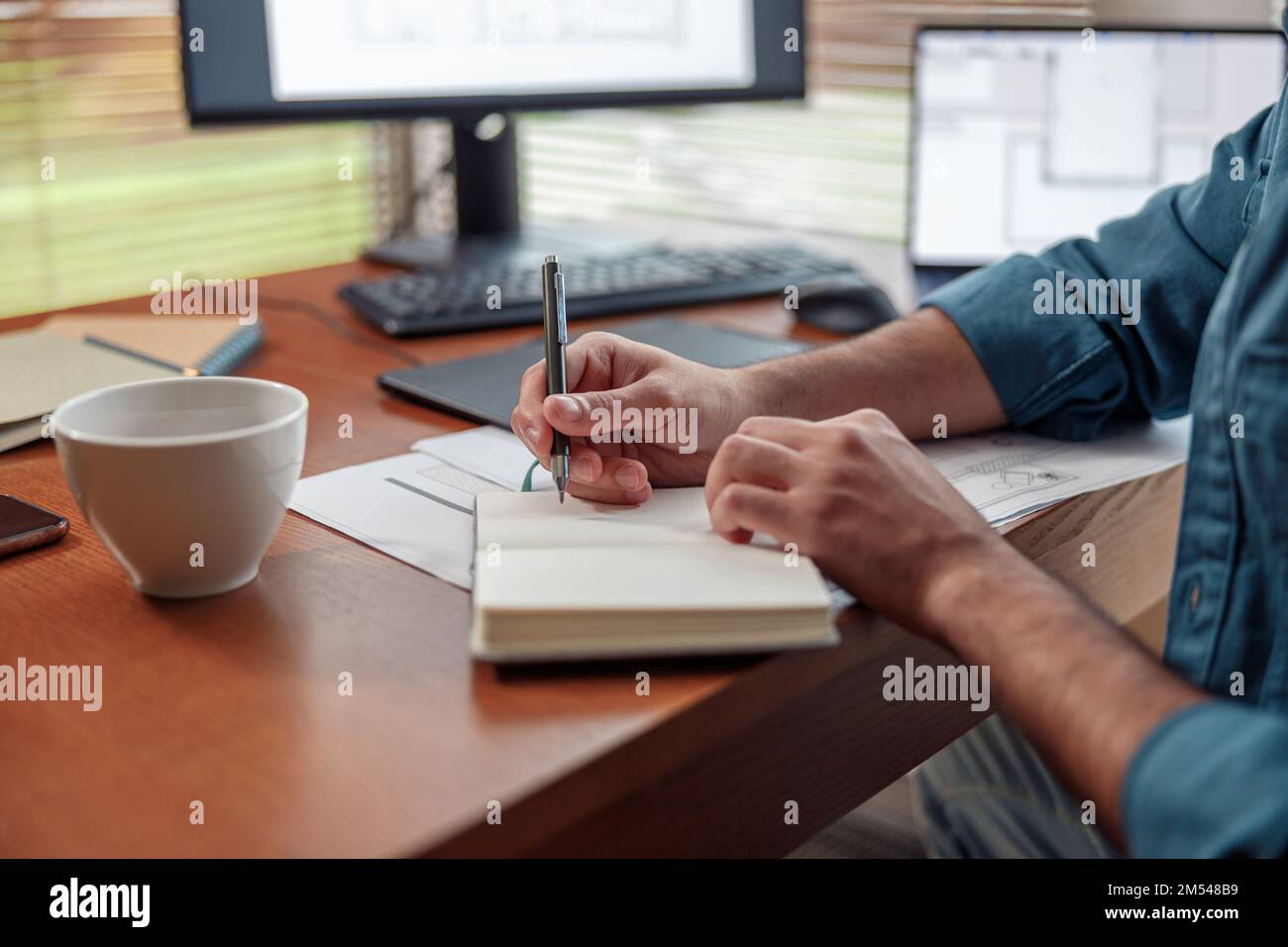 Close up of man hands making notes in notepad while sitting on his ...