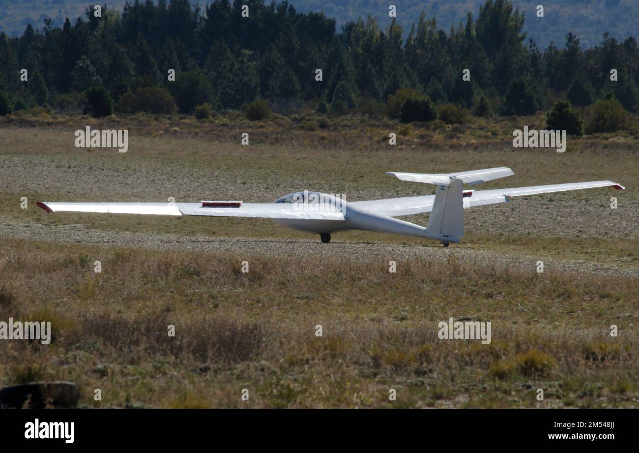 A ultralight glider plane flying near mountains, landing on earth ...
