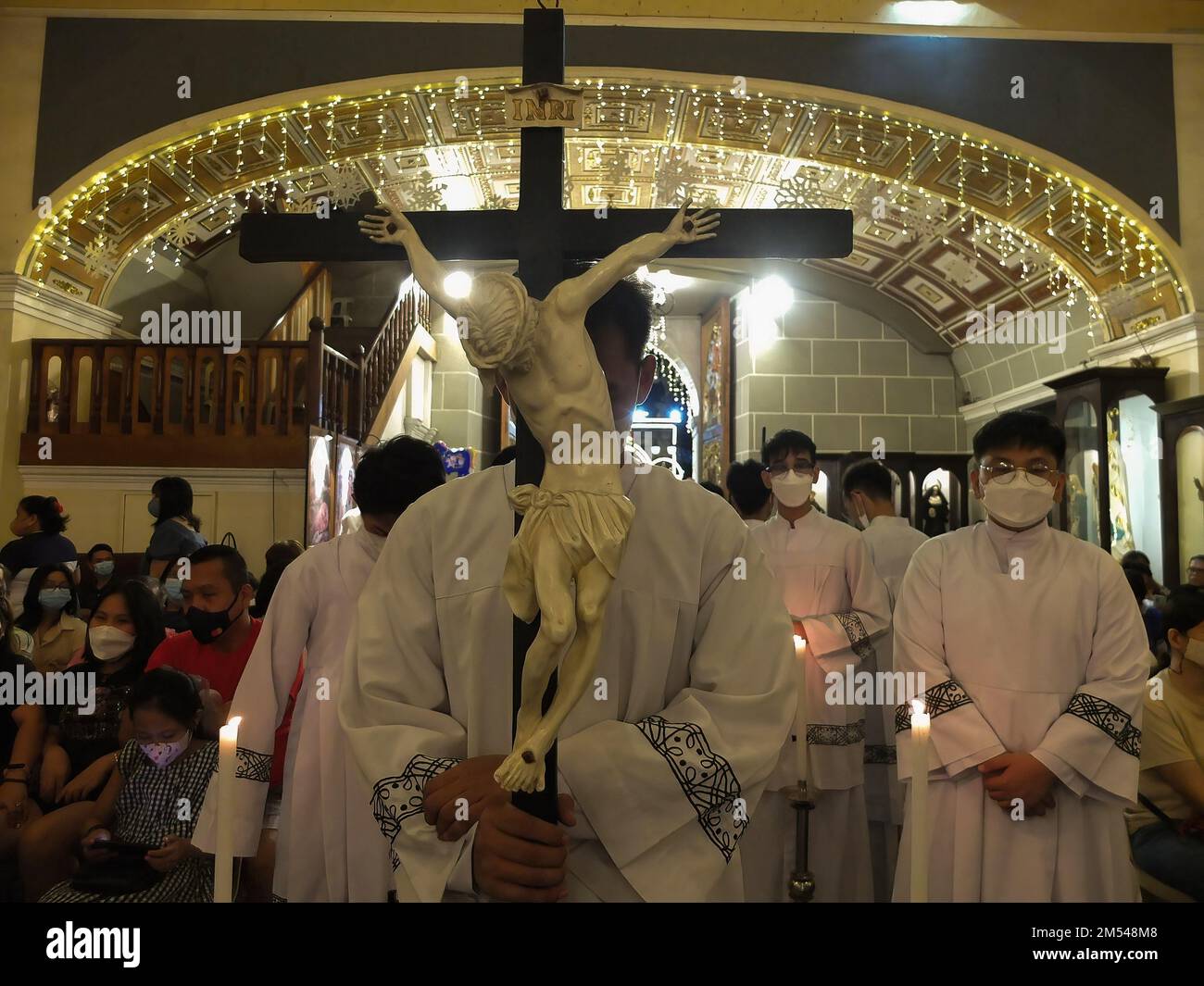 Malabon, Philippines. 24th Dec, 2022. A member of the Knights of the Altar holds a cross with a ...
