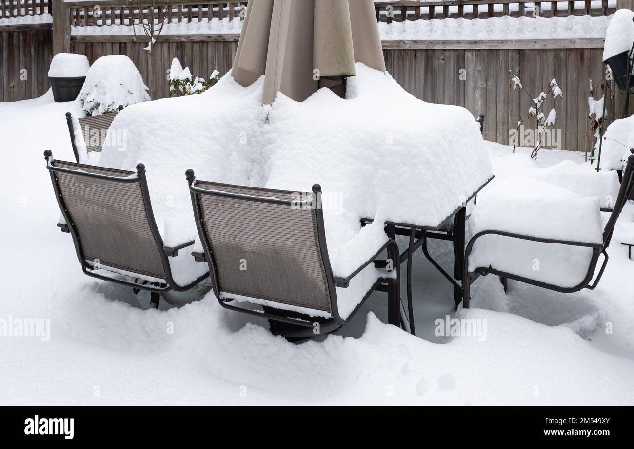 Outdoor furniture is covered with snow in a winter. Winter patio and ...