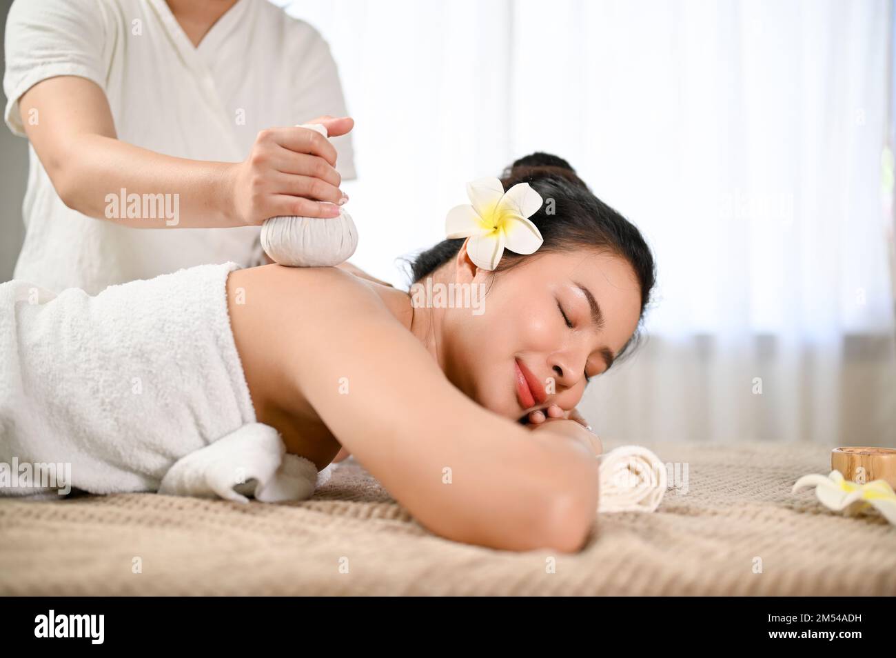 Attractive and charming Asian woman lying on spa massage table, eyes ...