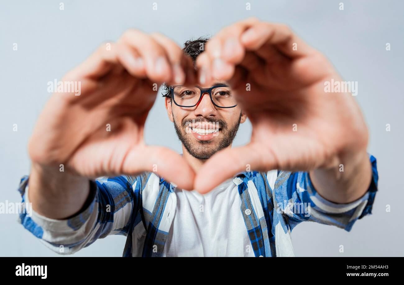 Person putting hands together in a heart shape. Teenage guy making ...