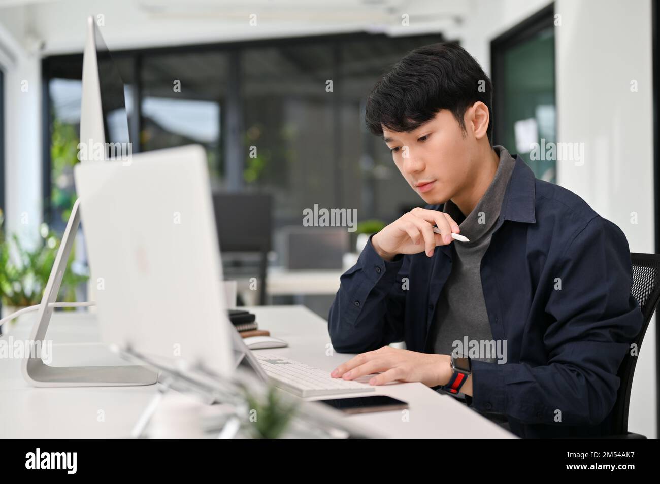 Handsome and smart young Asian male programmer working at his office ...
