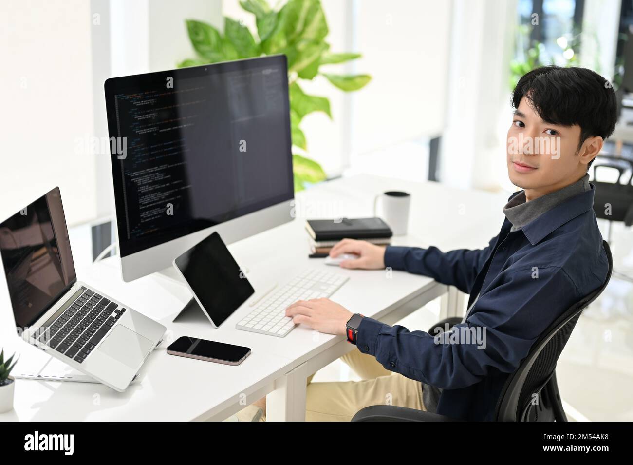 Professional and smart young Asian male programmer sits at his modern ...