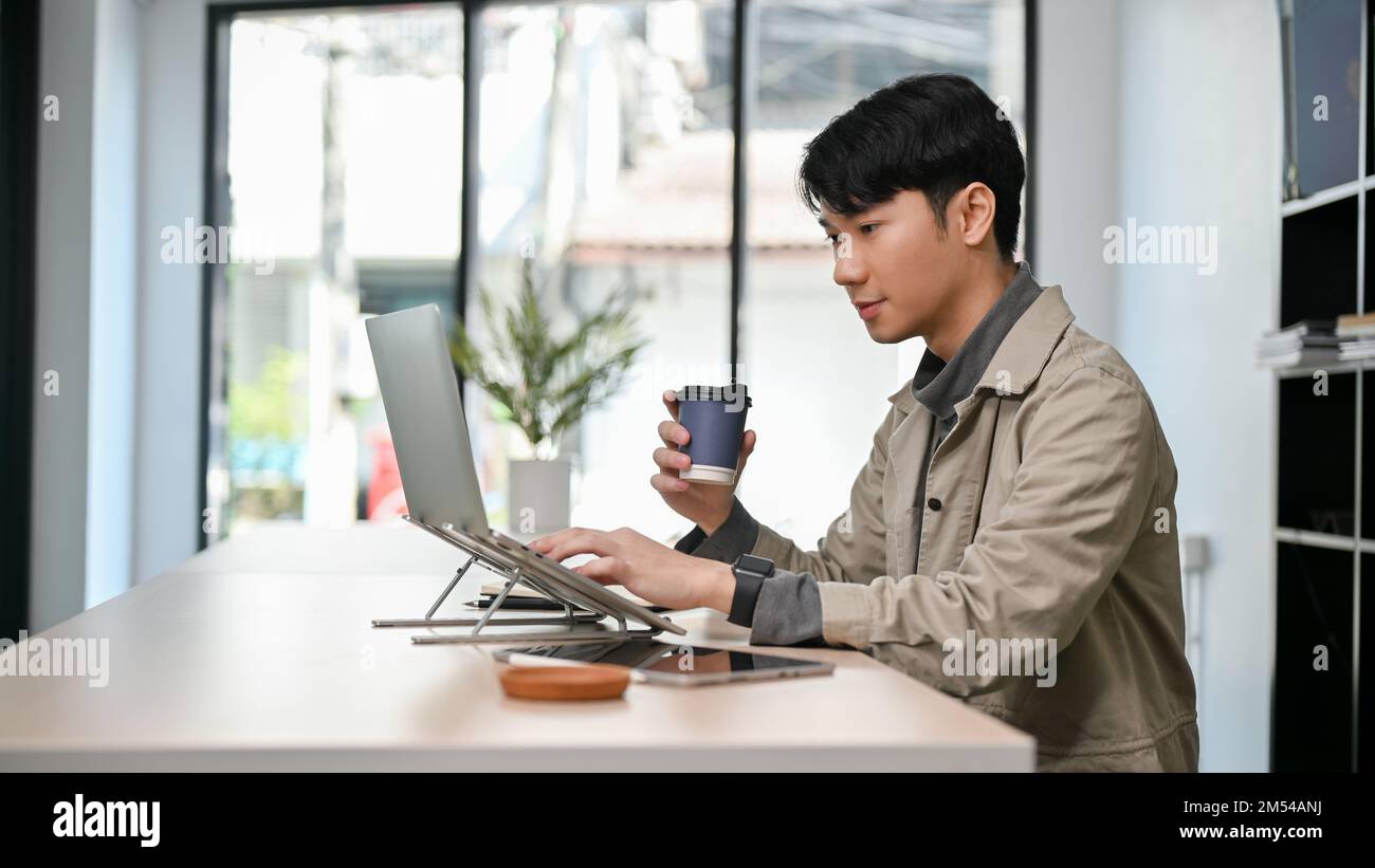 side view, Handsome and smart young Asian male programmer or freelance ...