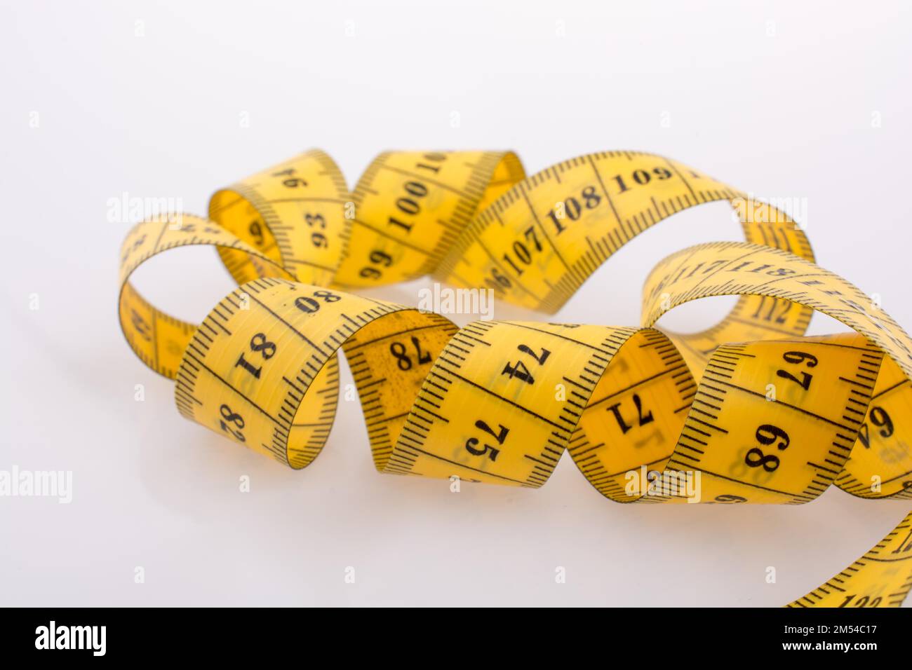 Yellow color measuring tape on a white background Stock Photo - Alamy