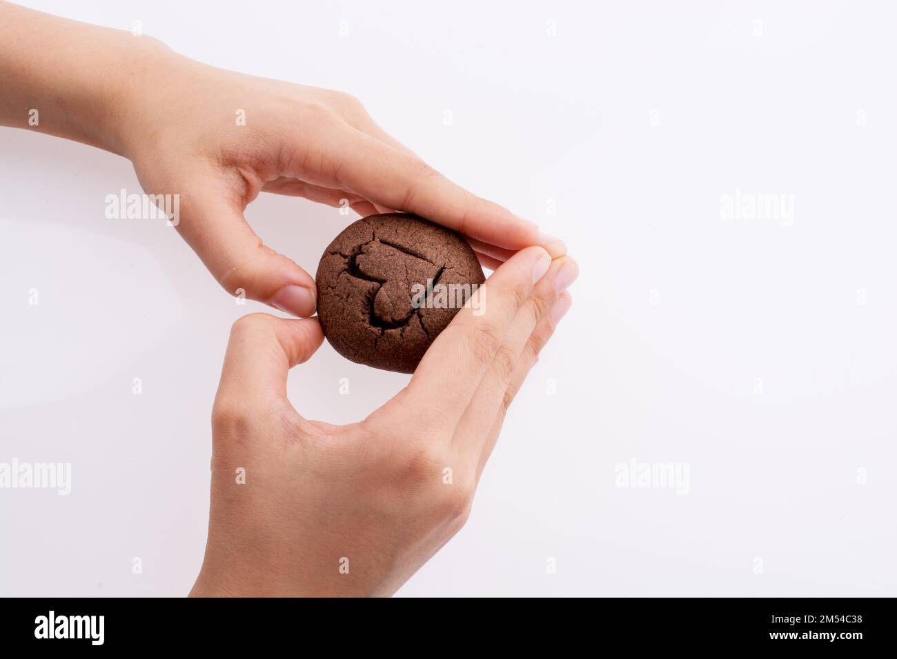 Hand holding a heart patterned chocolate cookie on a white background ...
