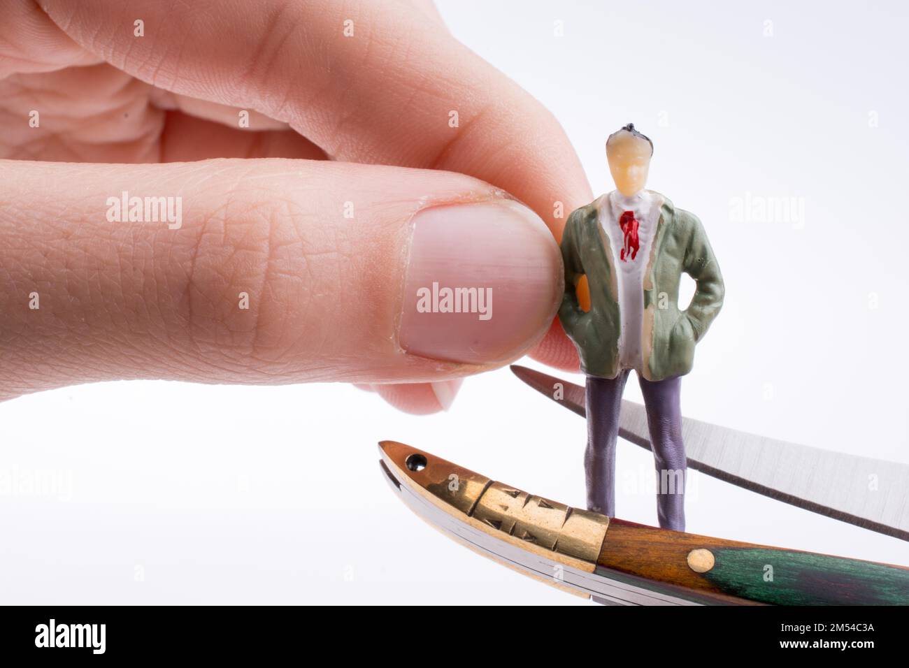 Hand holding a pocket knife near a human figure on a white background ...