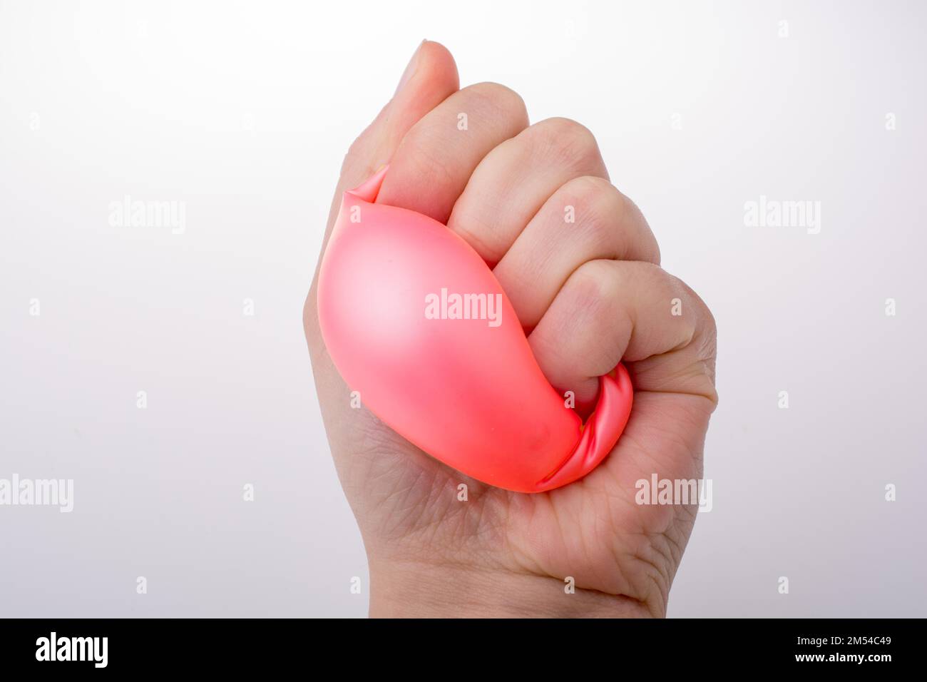 Squeezing pink balloon with hand on a white background Stock Photo - Alamy