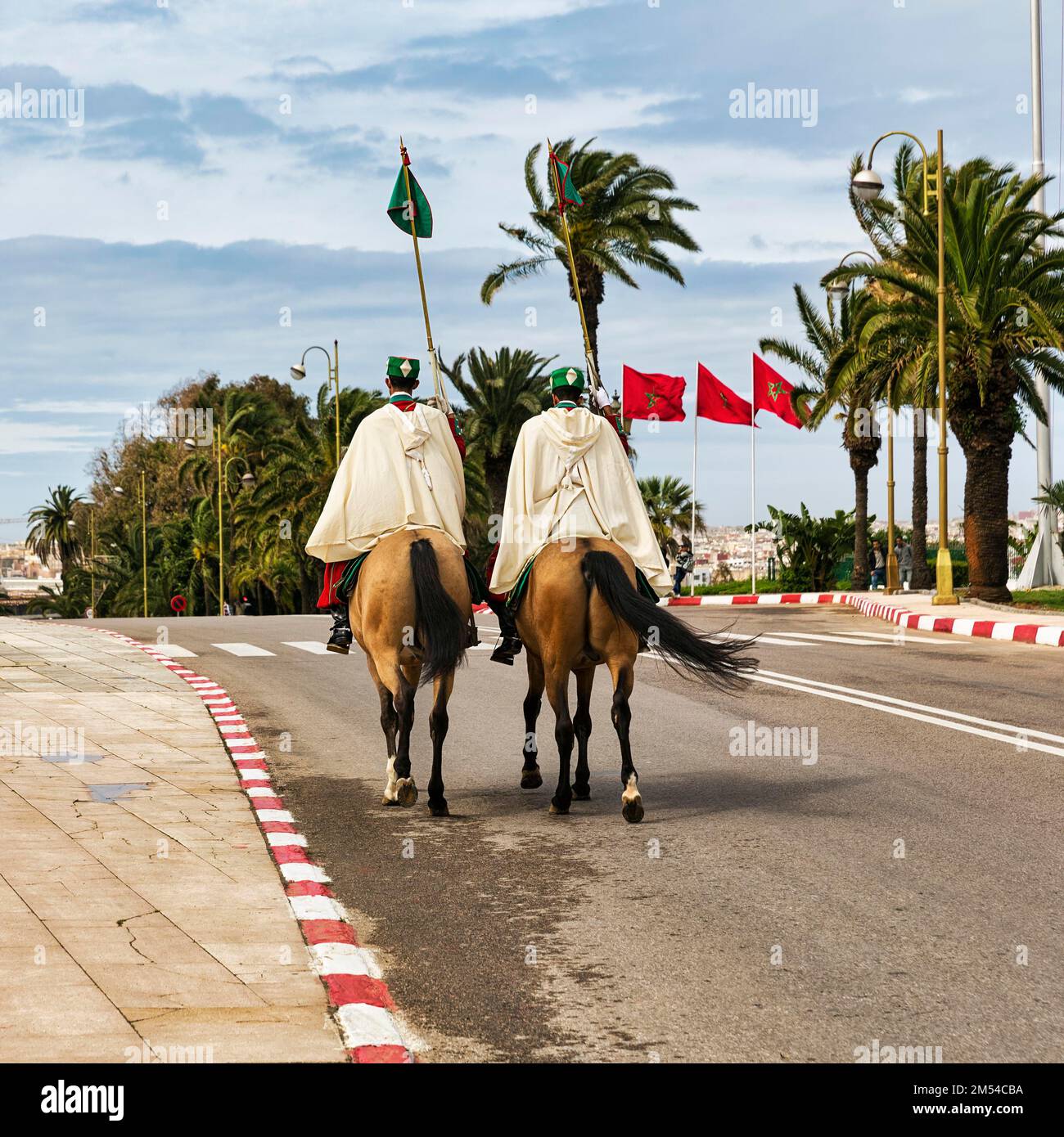Two mounted guards in traditional dress on the street, view from behind ...